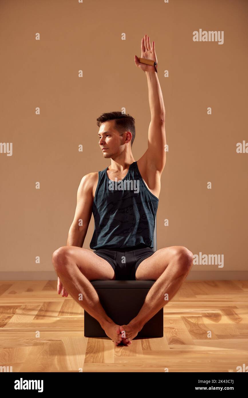 Handsome pilates male instructor performing stretching balance fitness ...