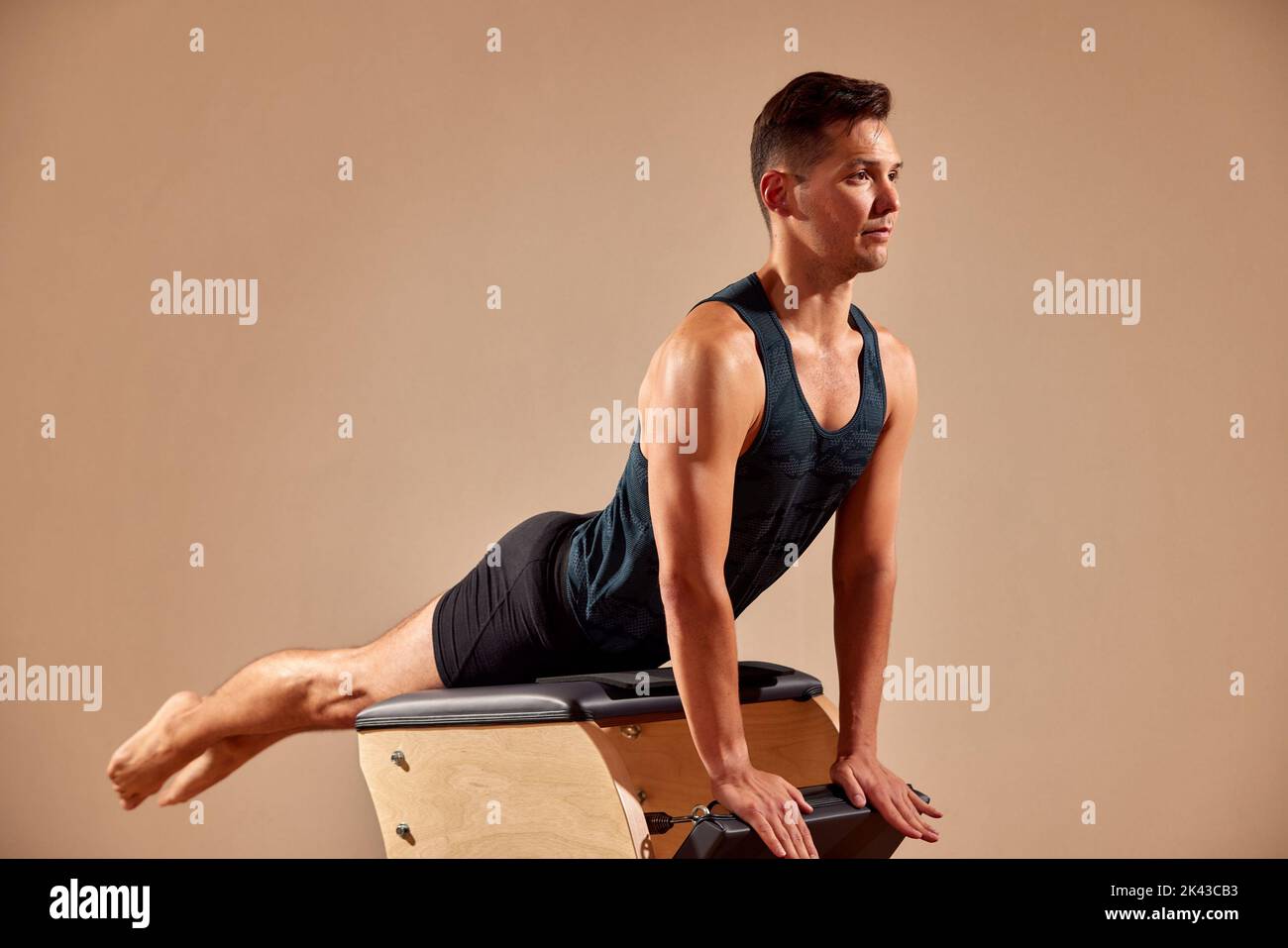 Handsome pilates male instructor performing stretching balance fitness ...