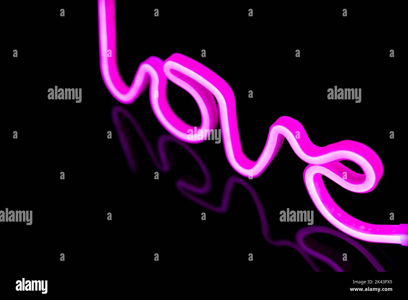 Image of vibrant neon love text formed with pink glow sticks over black ...