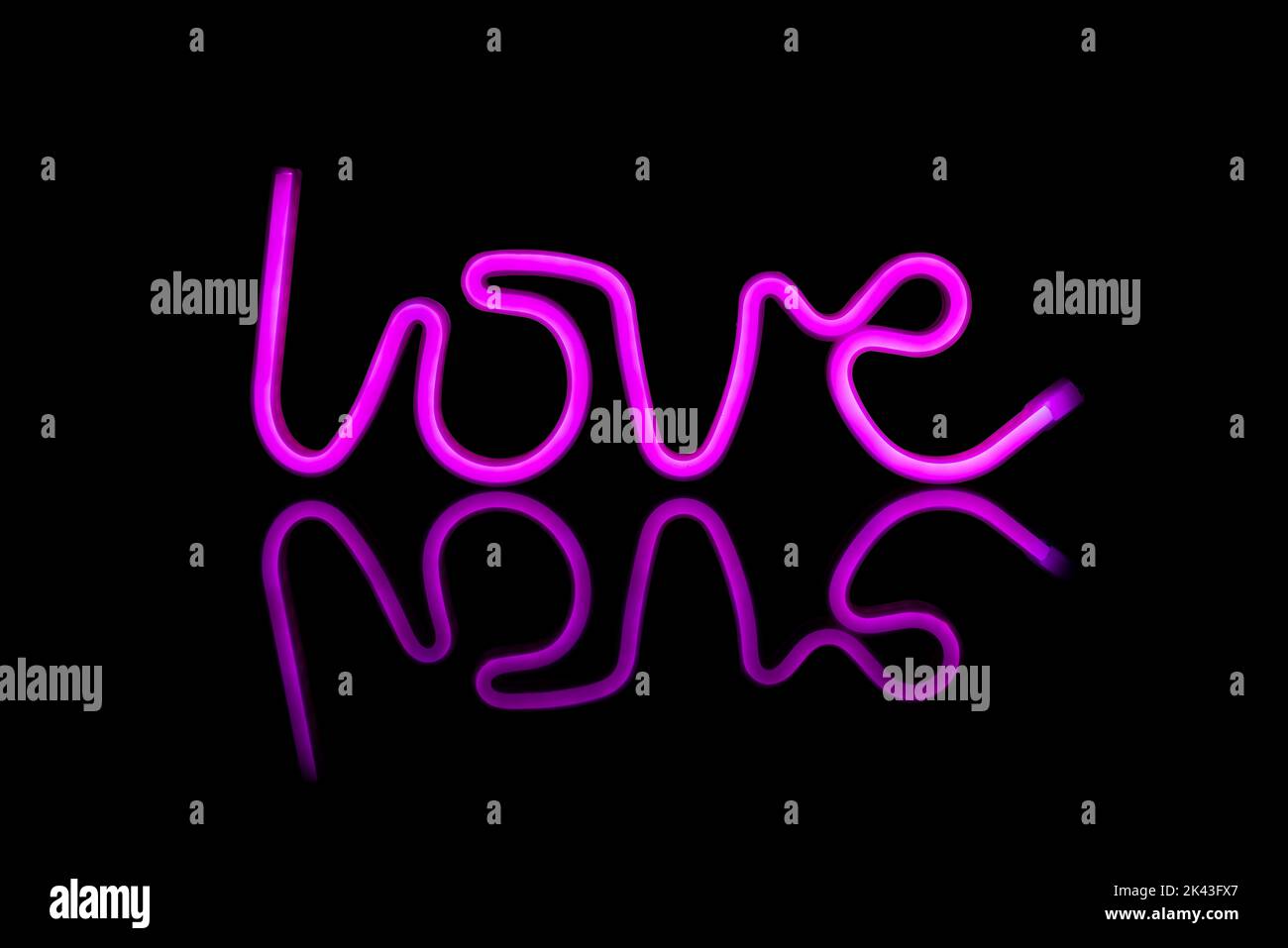 Image of vibrant neon love text formed with pink glow sticks over black ...