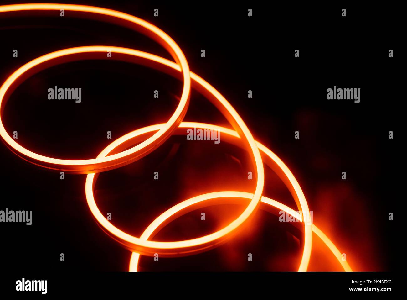 Image of vibrant spiral orange neon glow sticks over black background ...
