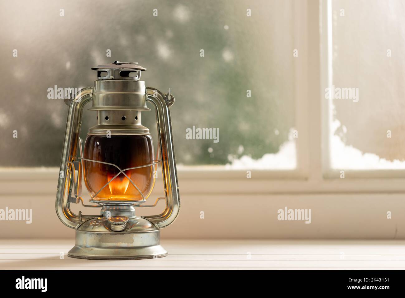 Vintage christmas shining oil lantern over frozen and snowy window ...
