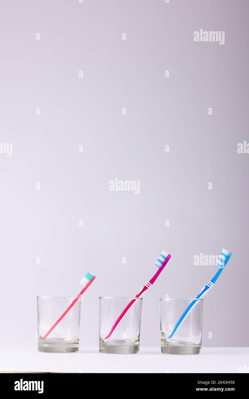 Vertical image of toothbrushes in glasses on grey background Stock ...