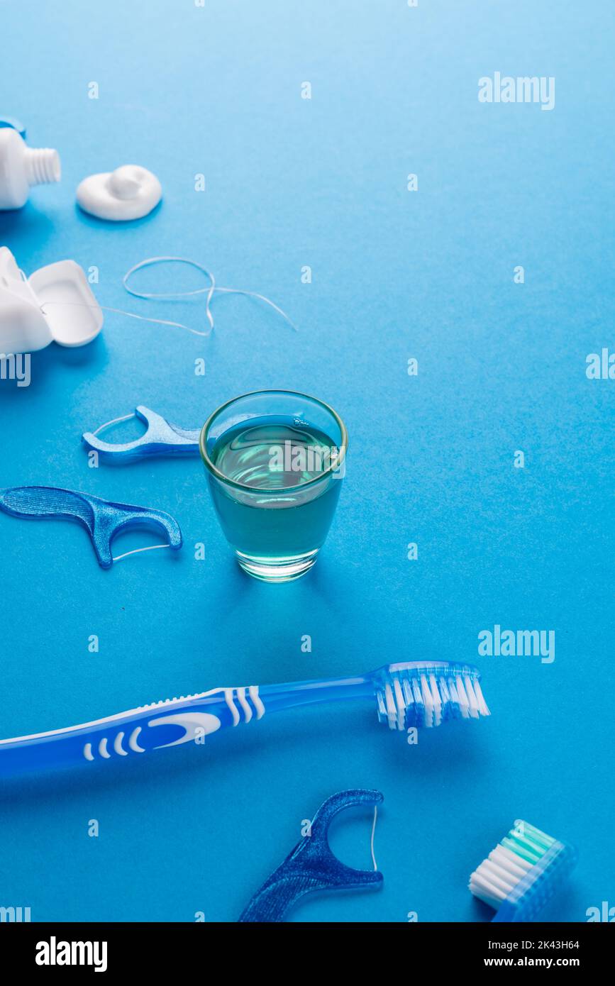 Vertical image of toothbrush, toothpaste, string and liquid on blue ...