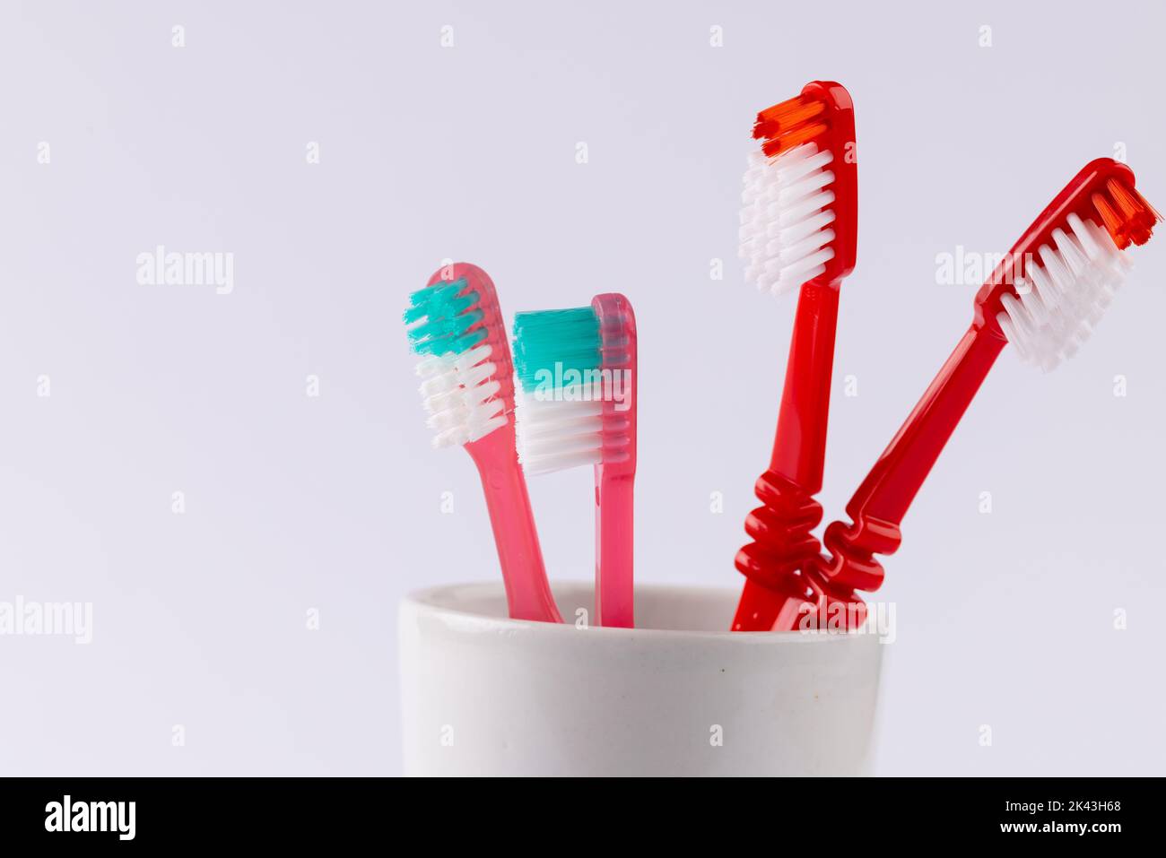 Image of toothbrushes in cup on grey background Stock Photo - Alamy