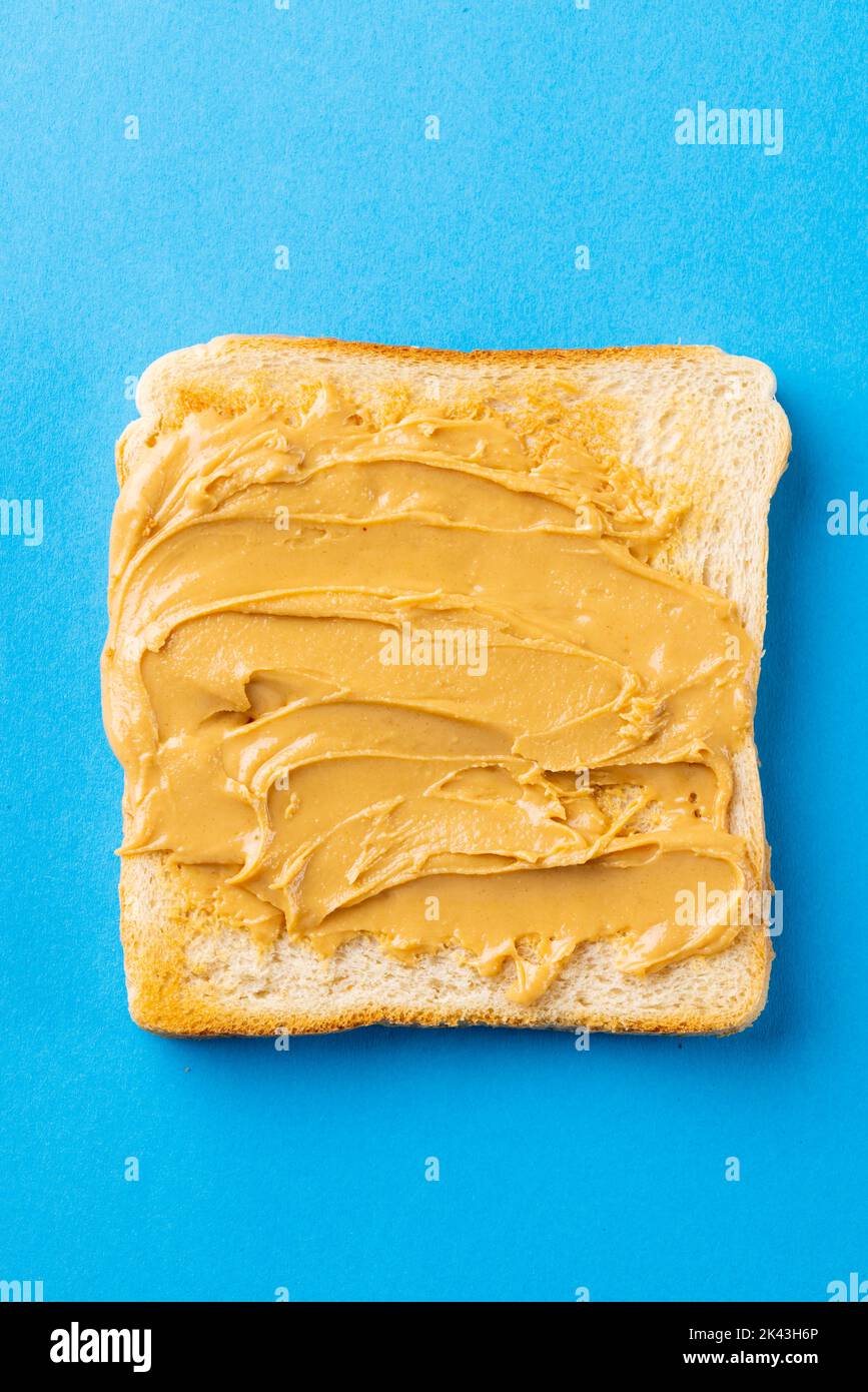 Vertical image of bread slice with peanut butter on blue background ...