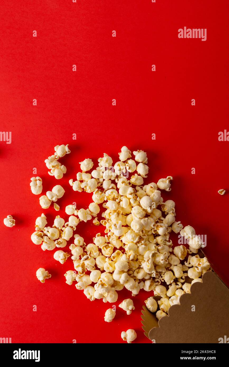 Vertical image of pop corn lying on red surface Stock Photo - Alamy
