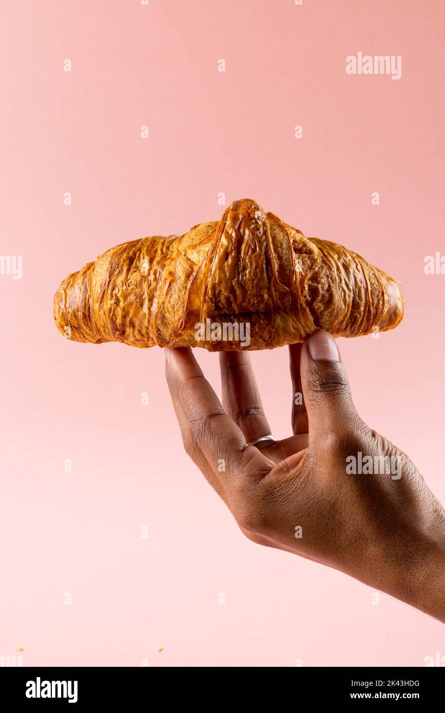 Vertical image of hands of african american man holding croissants on ...