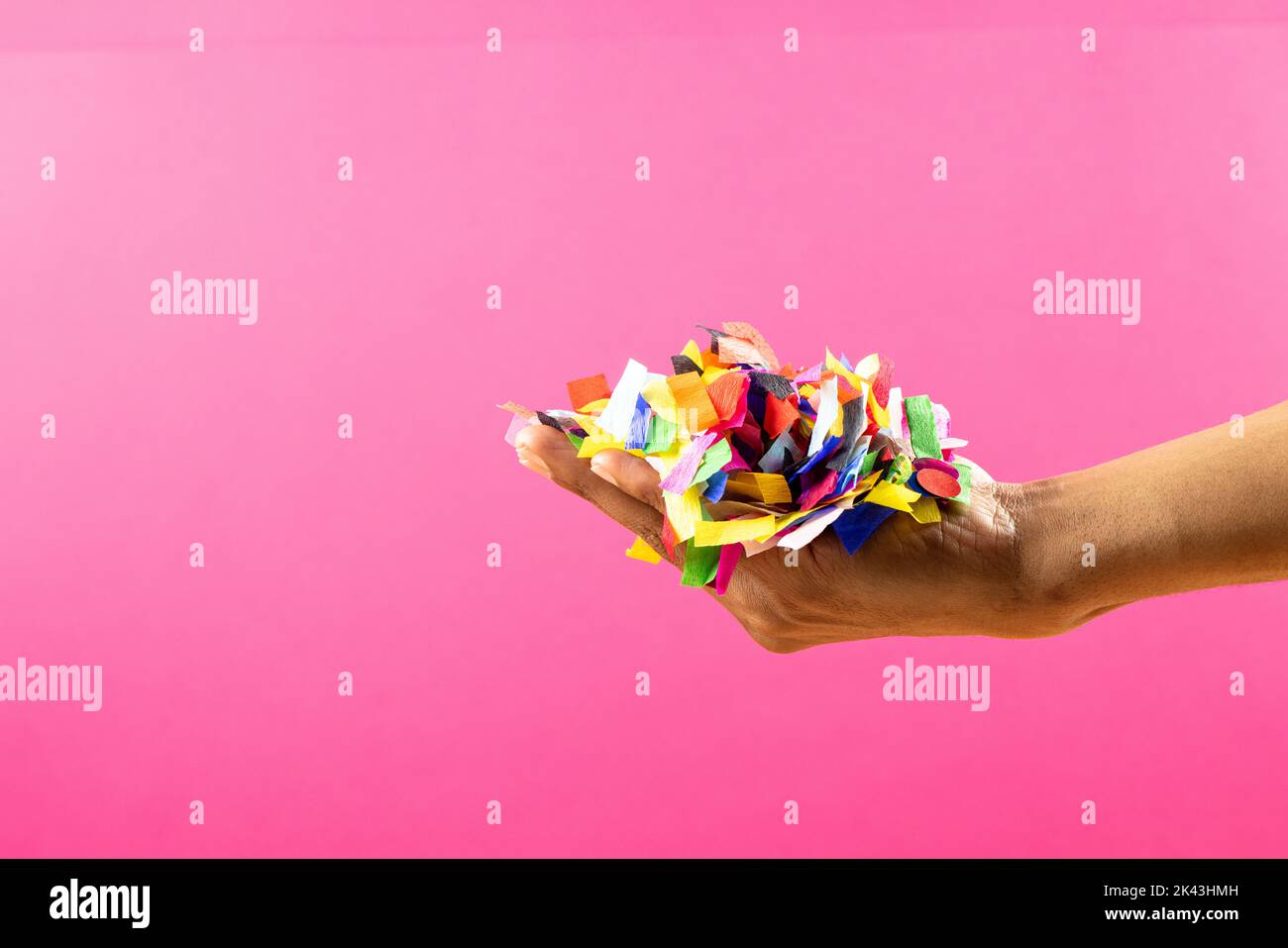 Composition of close up of hand with new years confetti on pink ...