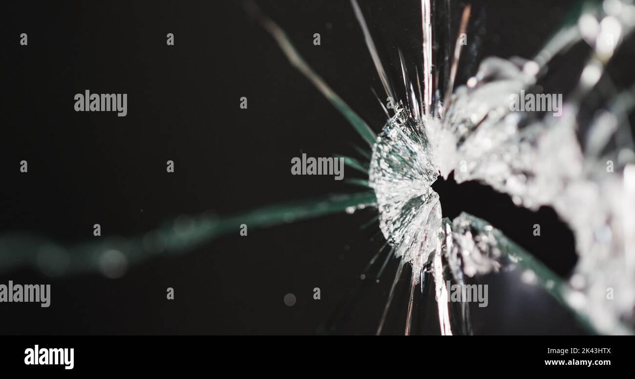Close up of broken, cracked pane of glass with hole, on black ...