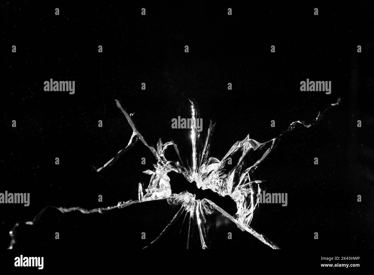 Close up of broken, cracked pane of glass with central hole, on black ...