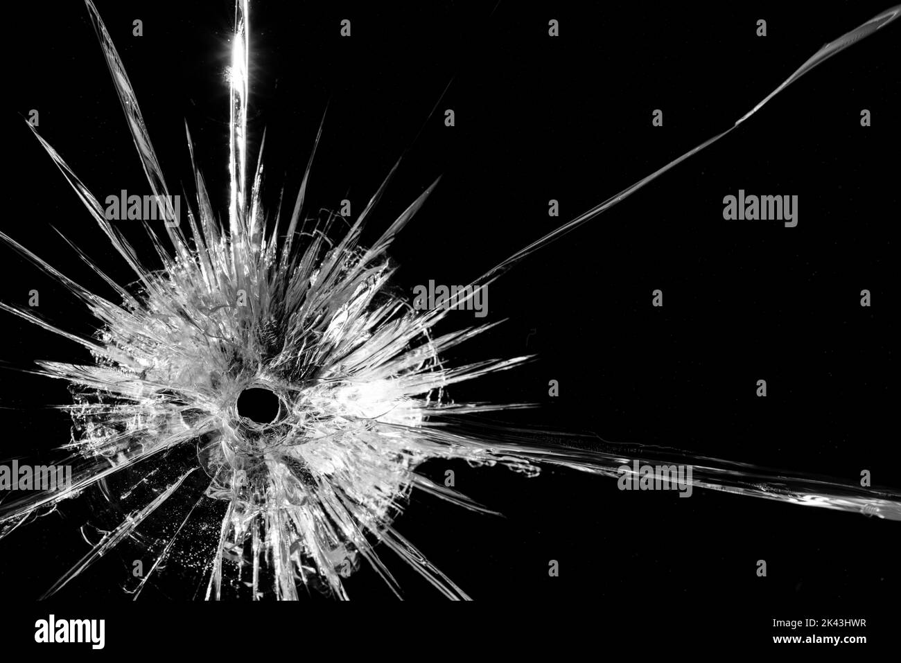 Close up of broken, cracked pane of glass with bullet hole, on black ...