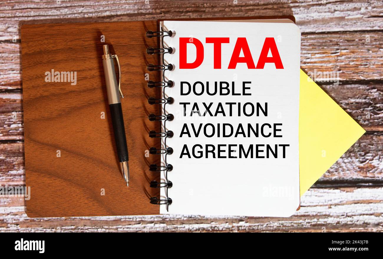 Closeup on businessman holding card with DTAA DOUBLE TAXATION AVOIDANCE ...