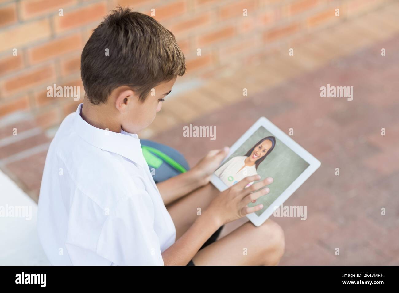 Caucasian schoolboy using digital tablet on video call with female ...