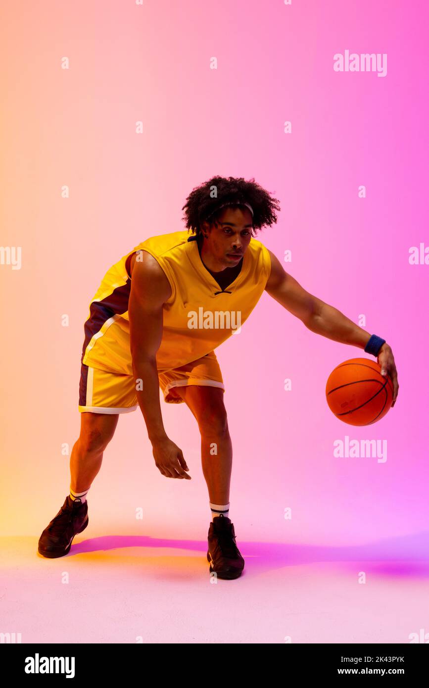 Image of biracial basketball player bouncing basketball on pink to ...