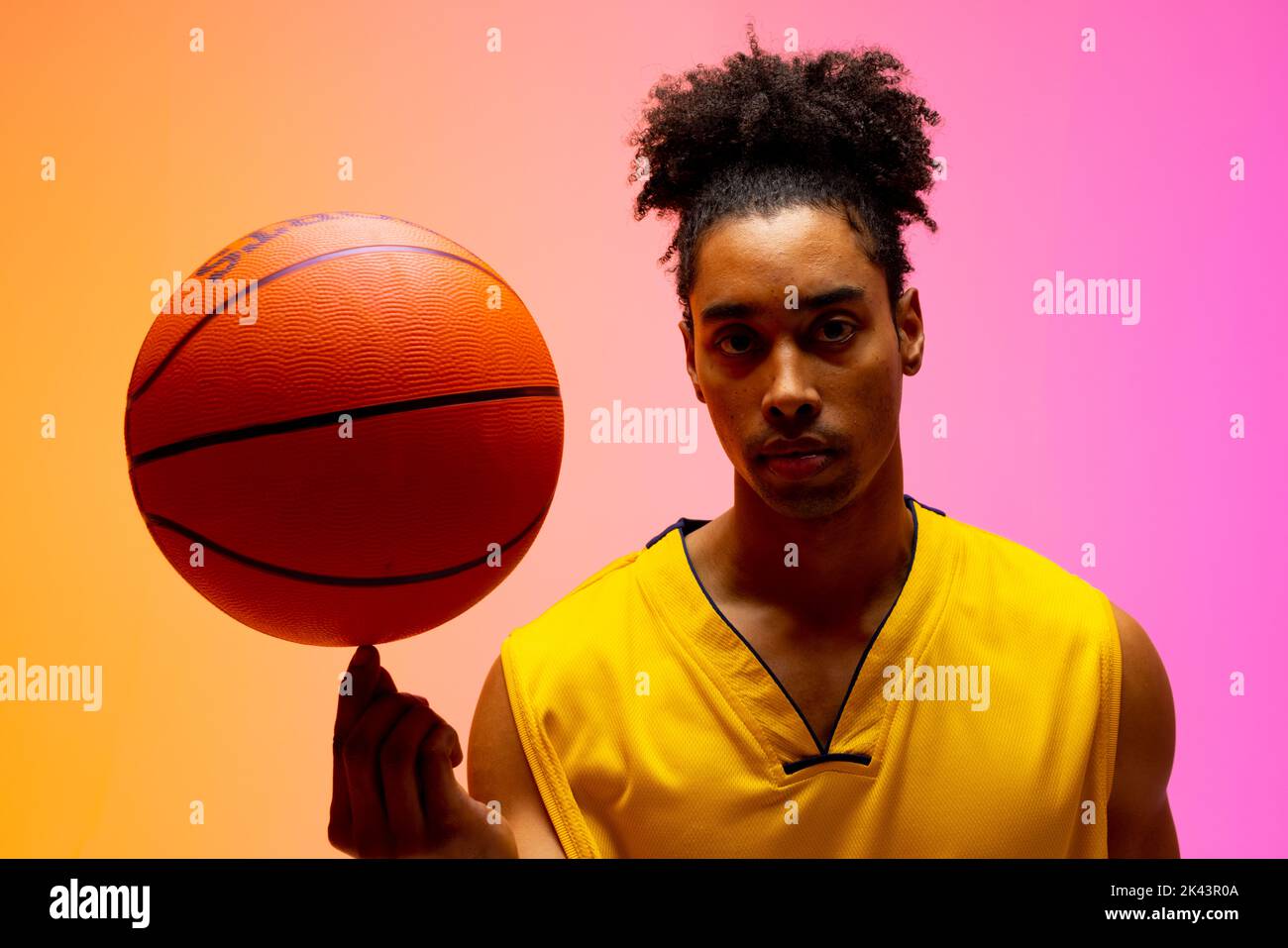 Image of biracial basketball player spinning basketball on pink to ...