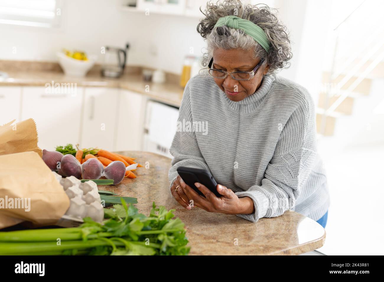 Senior african american women cooking alone in the kitchen and using ...