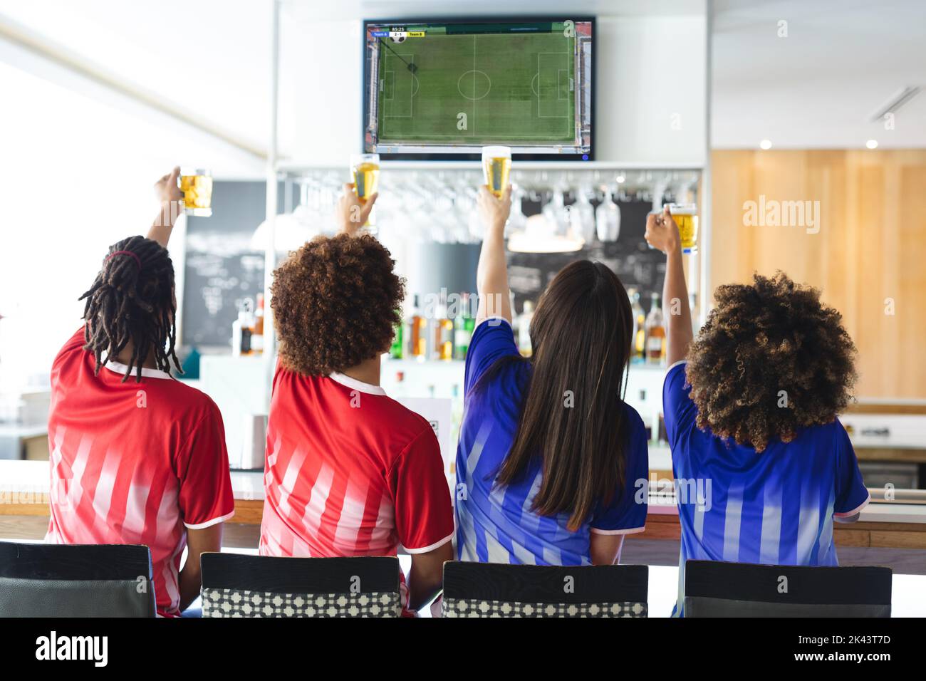Diverse friends supporting and watching tv in bar with football match ...