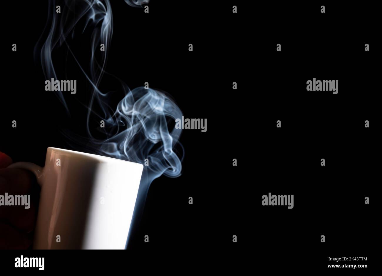 A white cup against a black background with smoke coming out of it ...