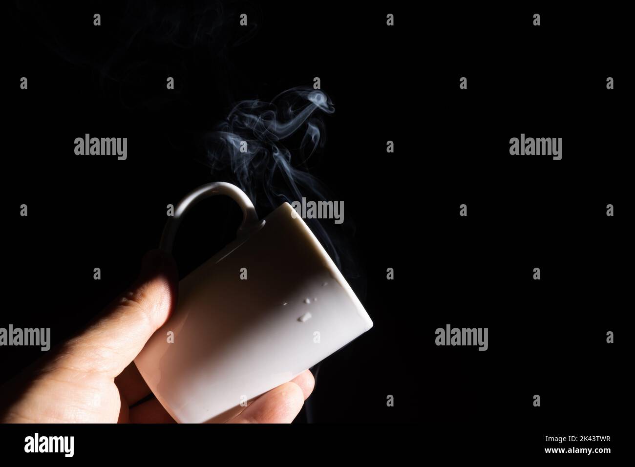 A white cup against a black background with smoke coming out of it ...