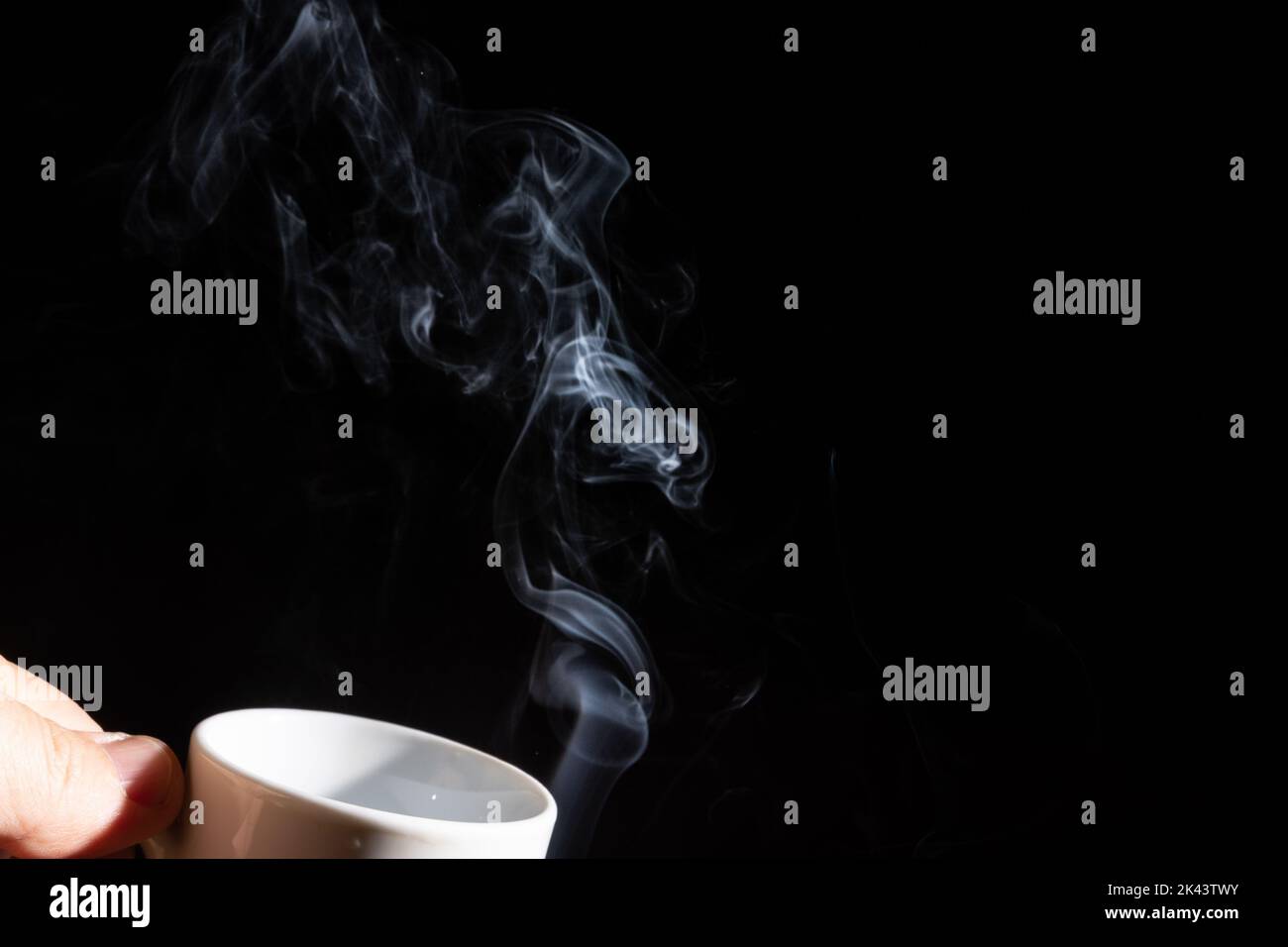 A white cup against a black background with smoke coming out of it ...