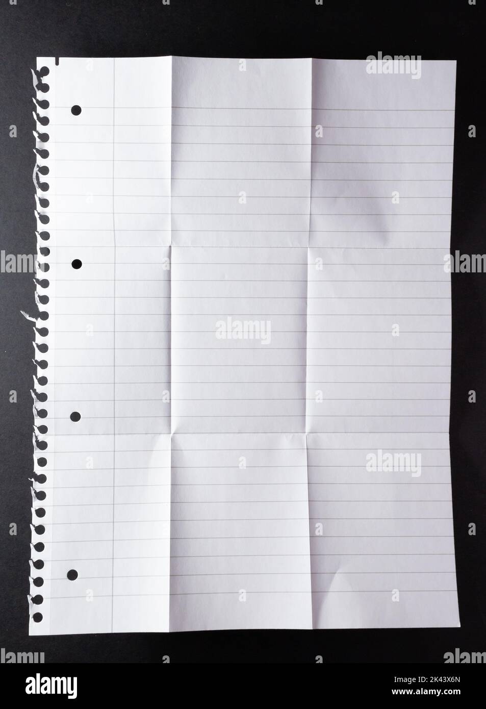 Hole punched sheet of lined paper, torn from spiral binding, folded ...