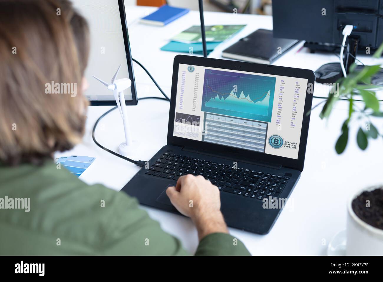 Caucasian businesswoman sitting at desk using laptop with statistical ...