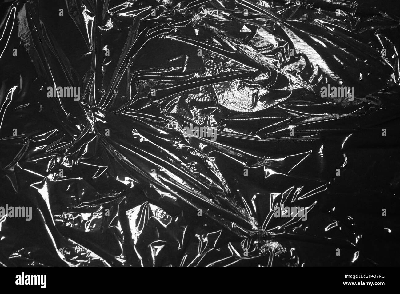 Reflecting light and shadow on creases and folds in black plastic ...