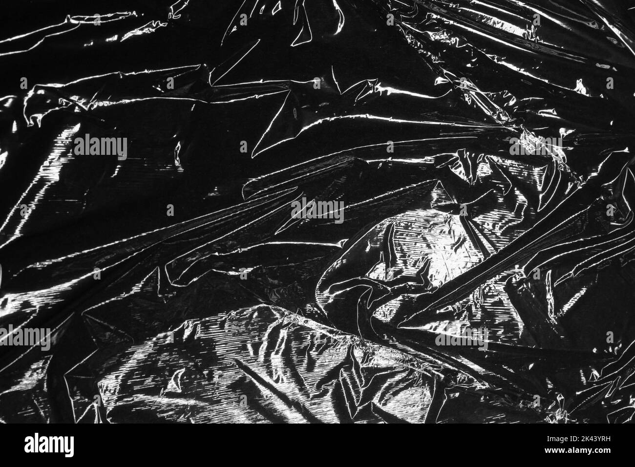 Reflecting light and shadow on creases and folds in black plastic ...