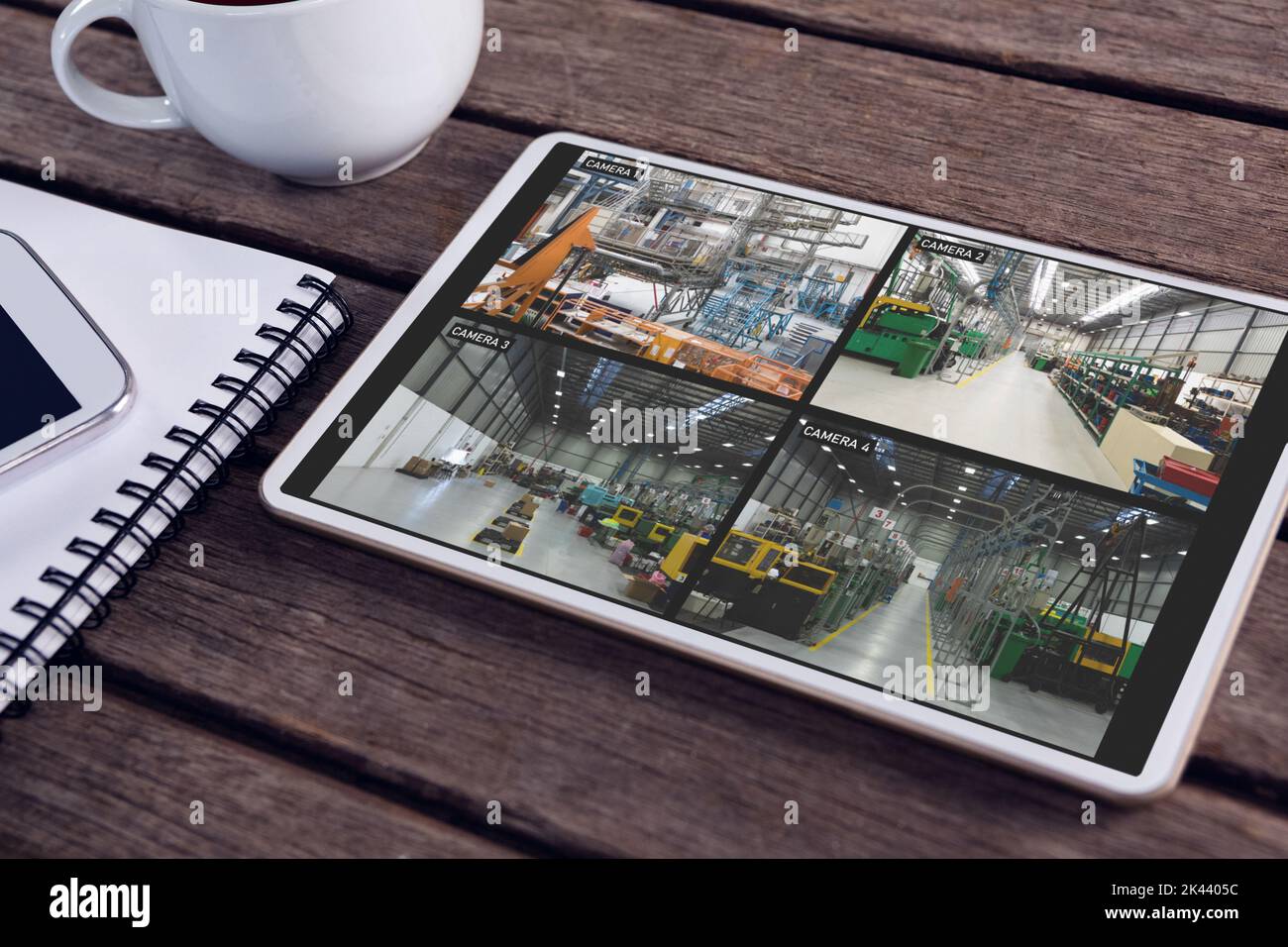 Tablet with views of warehouse from security cameras on screen lying on ...