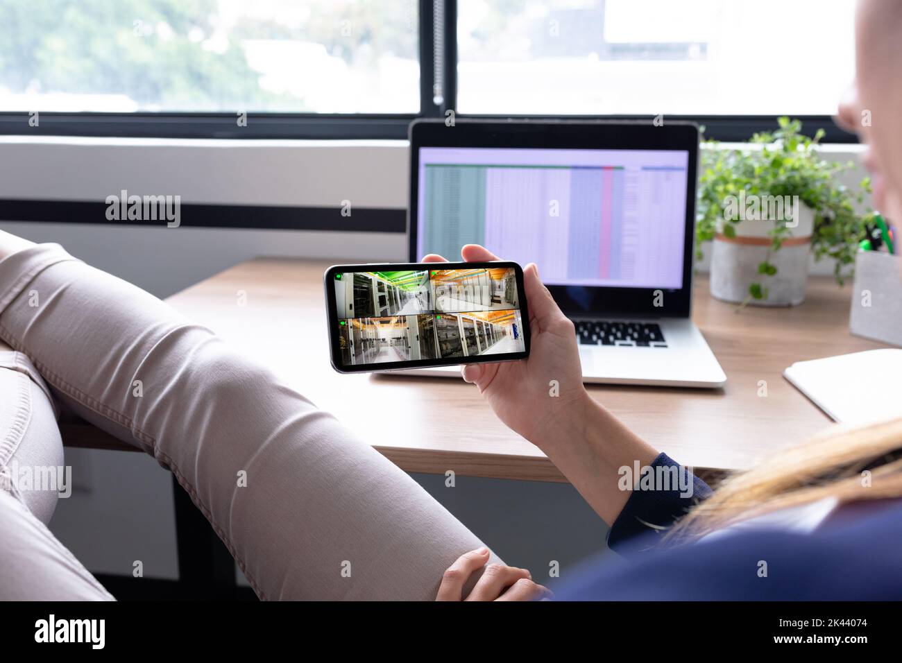 Caucasian woman in office using smartphone, views of server rooms from ...