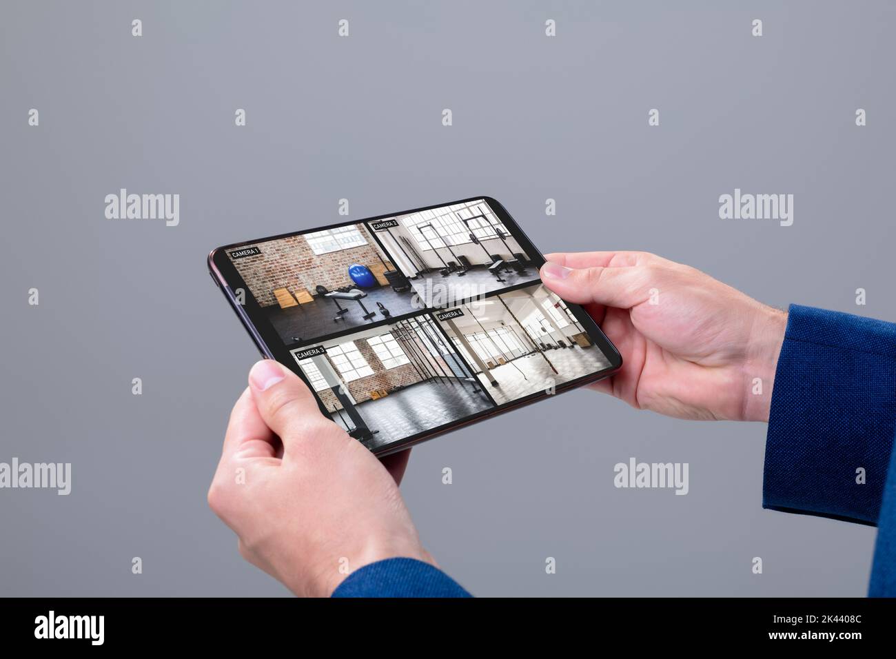 Hands of caucasian man holding tablet with view of gym from security ...