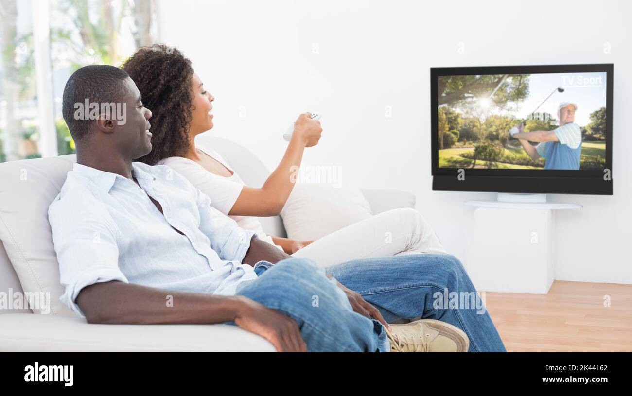 Couple sitting on couch together watching tv at home in the living room ...
