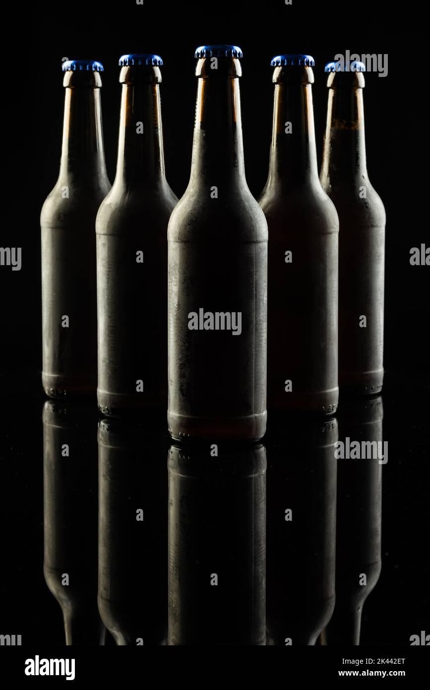 Vertical image of five dark glass bottles of lager beer with blue caps ...