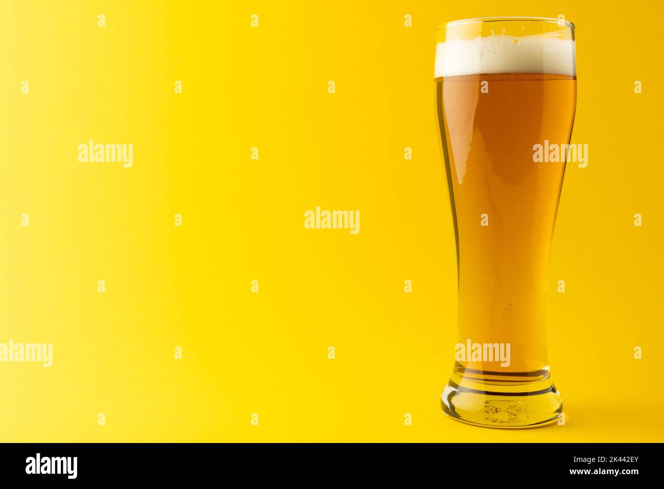 Image of full pint glass of lager beer, with copy space on yellow ...