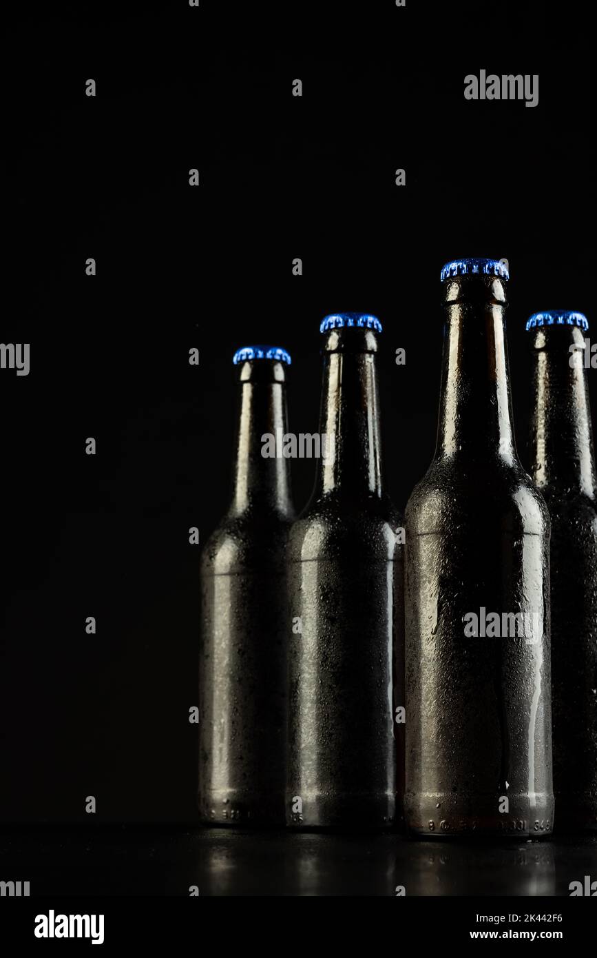 Vertical image of four dark glass bottles of lager beer with blue caps ...