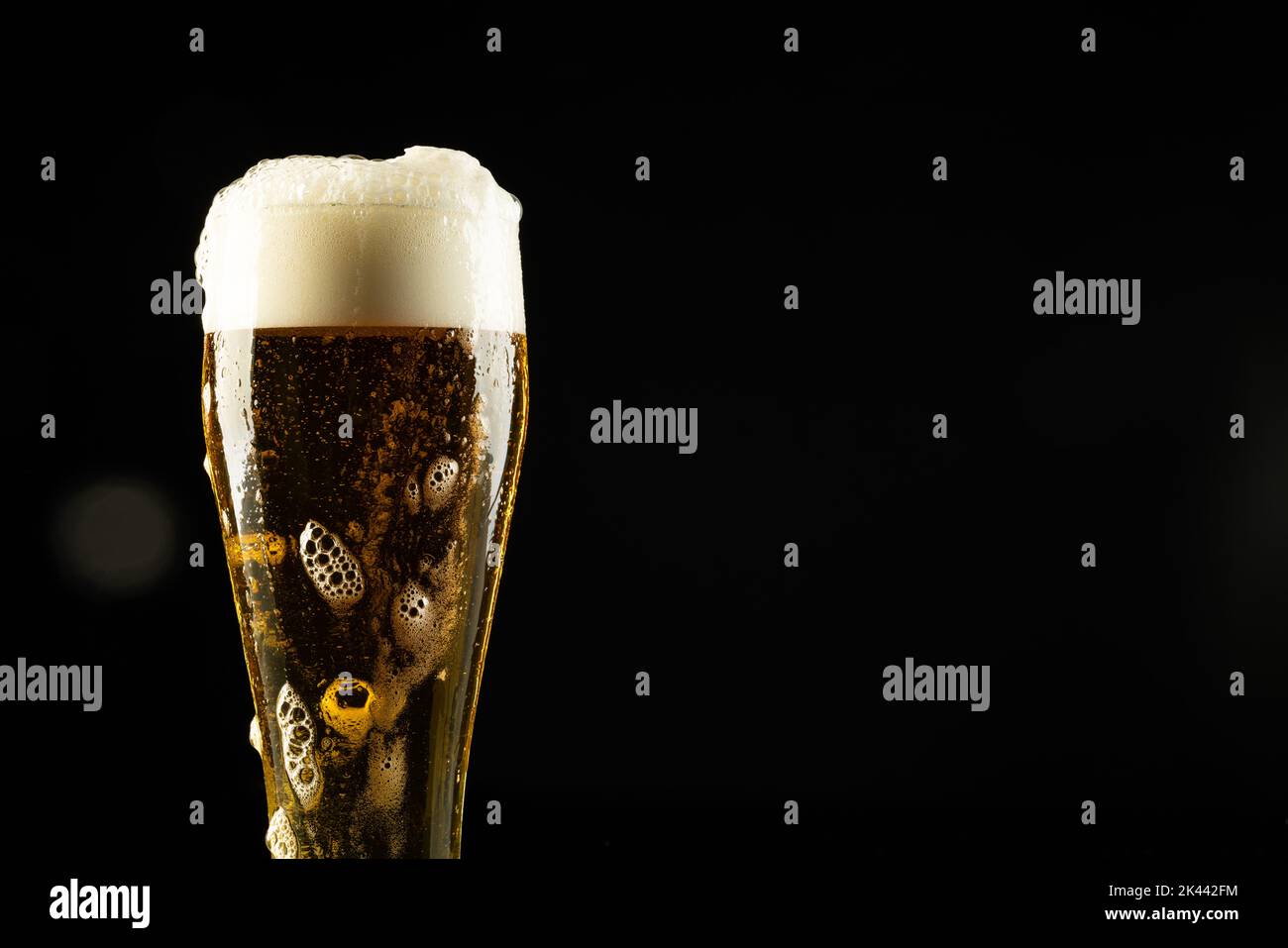 Image of full pint glass of foamy beer, with copy space on black ...