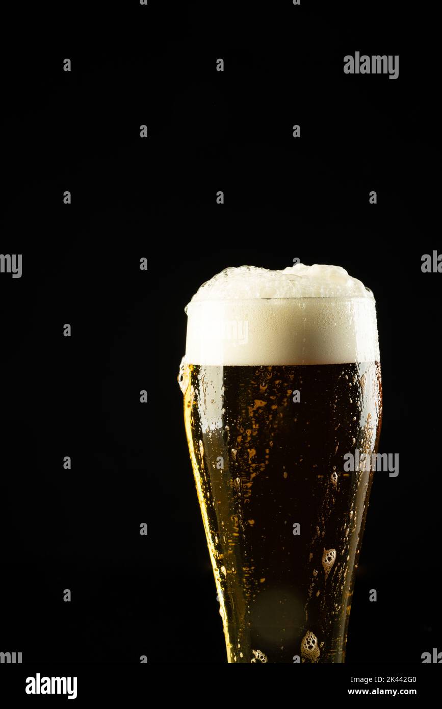 Image of full pint glass of foamy beer, with copy space on black ...