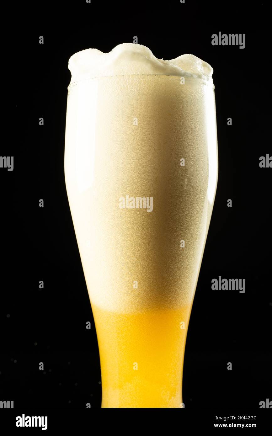 Image of overflowing pint glass of foamy beer, with copy space on black ...
