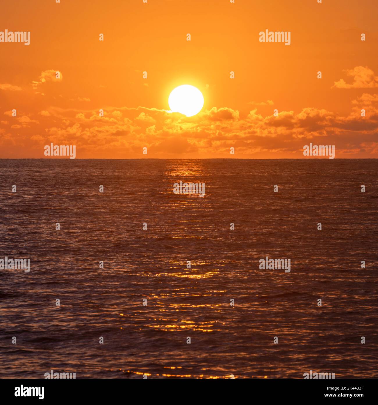 Sun rising above calm ocean Stock Photo - Alamy