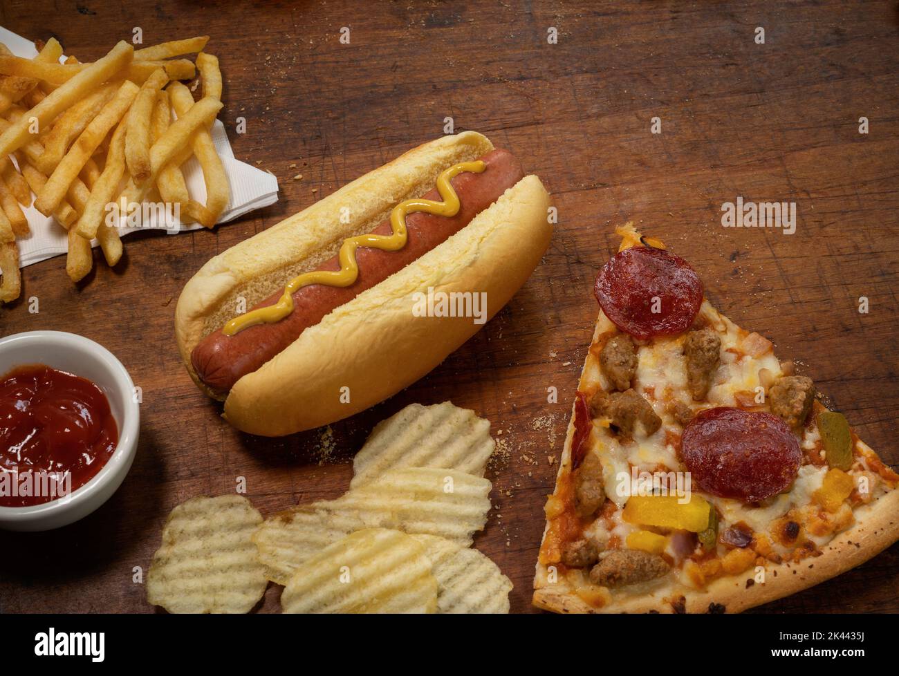 Variety of processed foods with pizza, hot dog, chips, and french fries ...