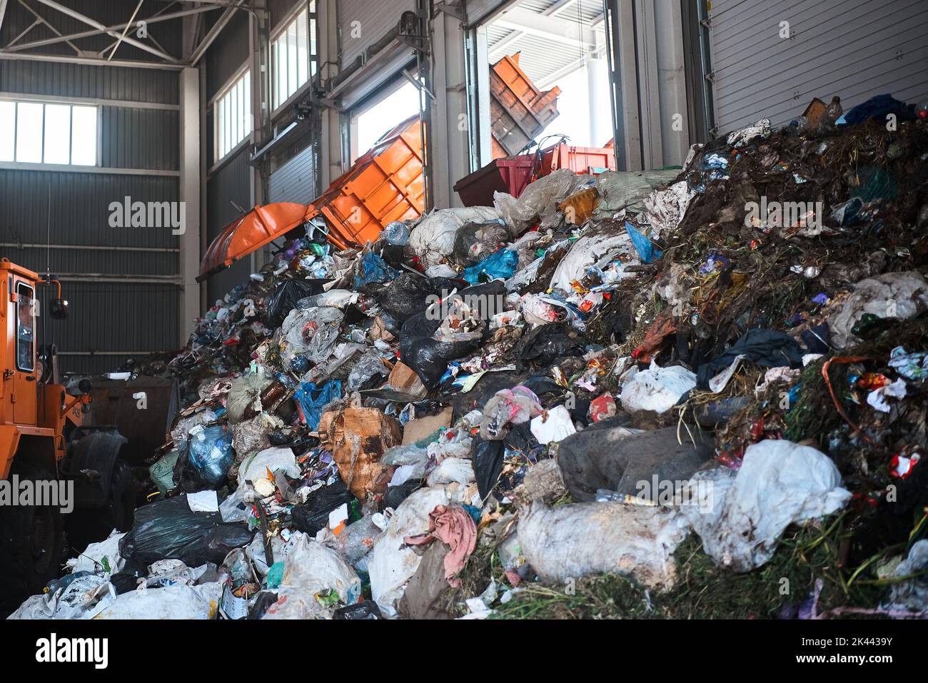 A garbage truck unloads household waste in the receiving chamber of a ...