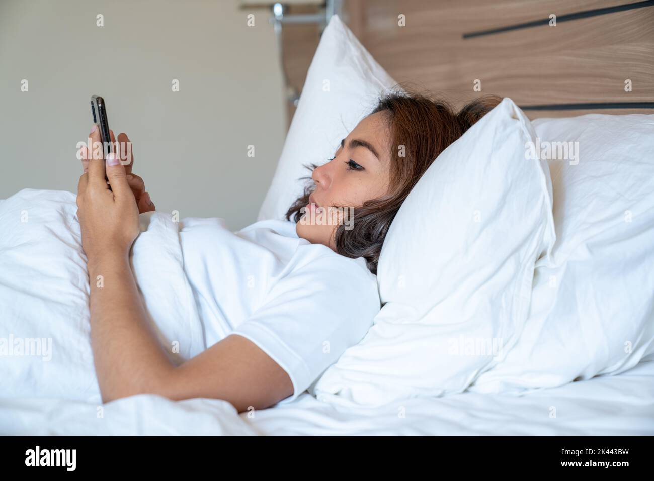 Young asian women lying in bed texting and checking social apps in ...