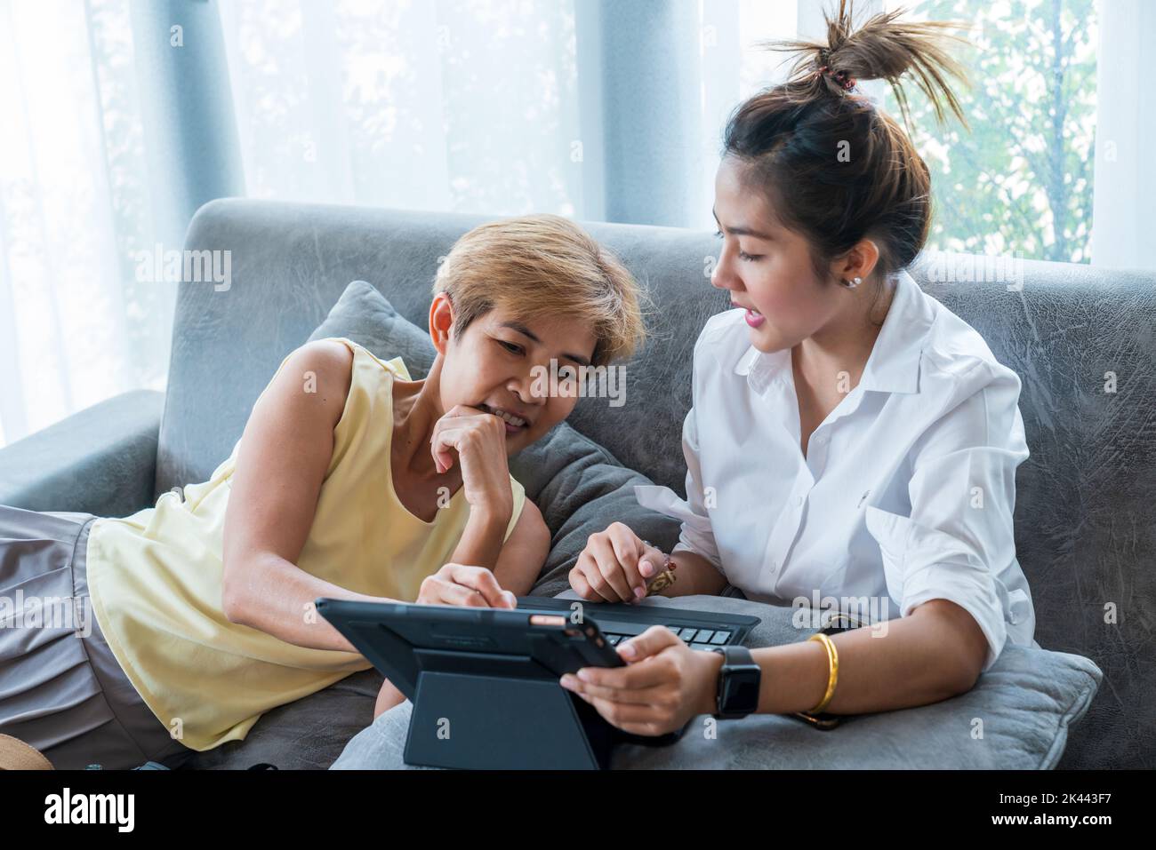 Grandma and grandson play the tablets on the sofa. Exchange knowledge ...