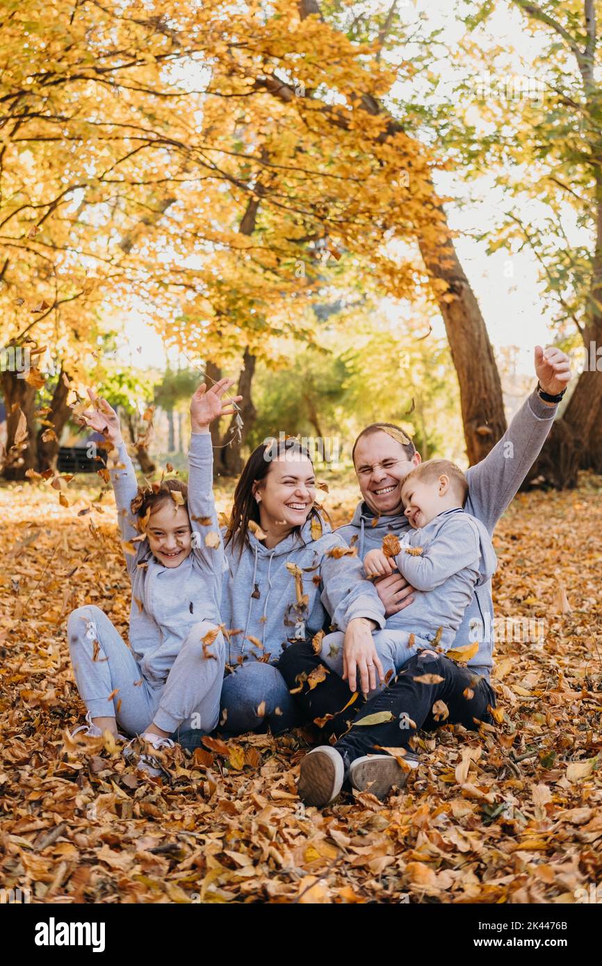 Happy extended family tossing autumn leaves in park in autumn. People ...