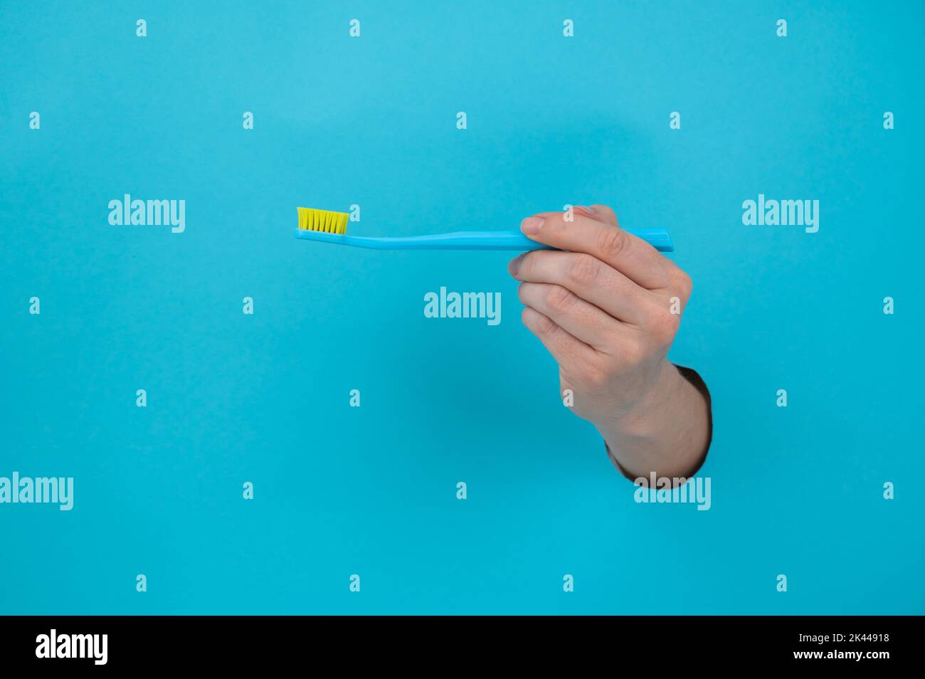 A woman's hand sticks out of a blue paper background and holds a ...