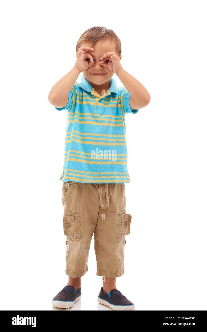 Peek-a-boo. Full length studio shoot of a cute young boy peeking at the ...