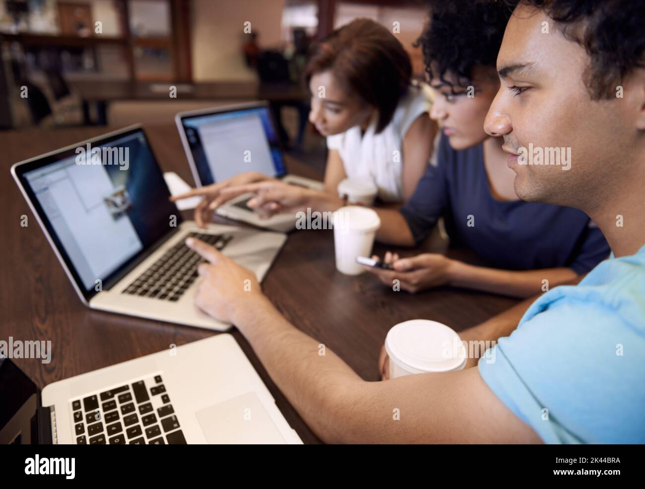 Study group dynamics. A group of students using a laptop to complete a group assignment Stock ...
