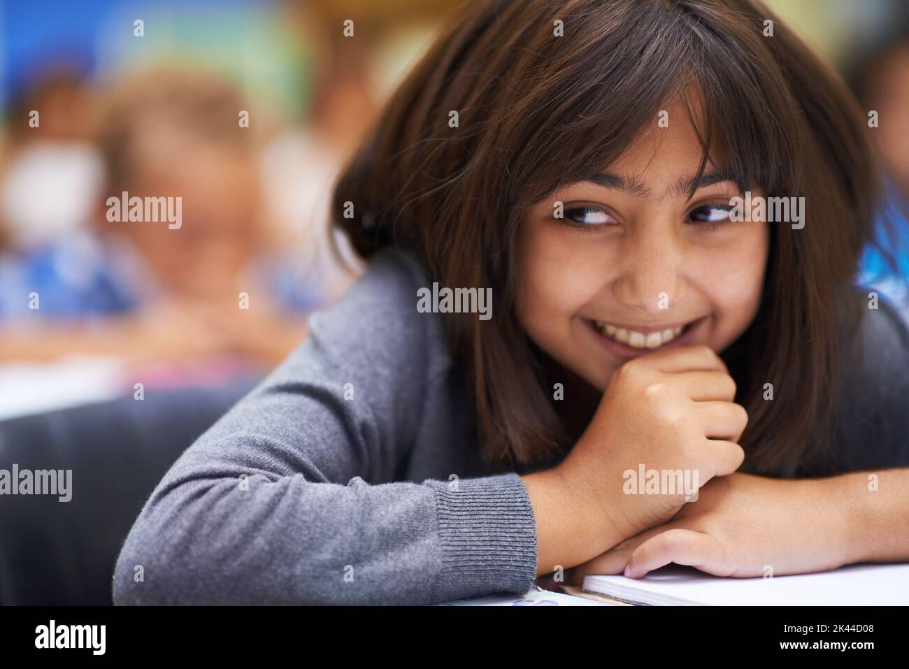 Having a giggle in the classroom. A young girl working on her ...