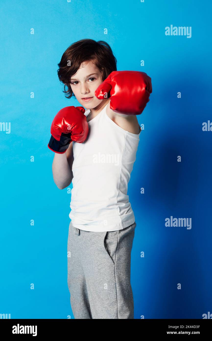Hes ready for a fight. Portrait of a young boy wearing boxing gloves in ...